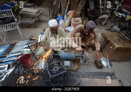 A Pakistani vendor sharpen axe which will be used to animal ...