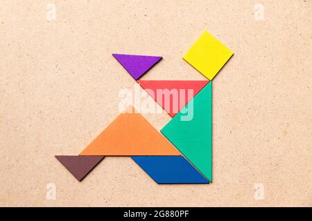 Color tangram in sitting man shape on wood background Stock Photo - Alamy