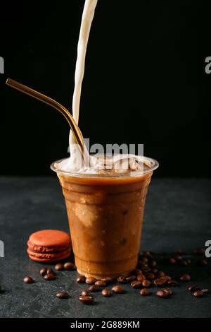 Plastic cup of iced coffee with macaroon on dark background Stock Photo ...