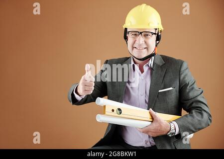 Engineer holding blueprints and showing thumbs up isolated on white ...