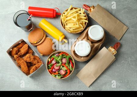 Different fast food on gray textured table Stock Photo - Alamy