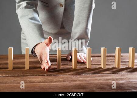 Business woman interrupting domino effect Stock Photo - Alamy