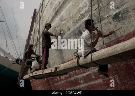 Maintenance workers repairing the hull of a phinisi ship at Sunda ...