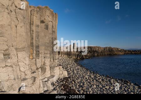 Basalt cliff, beach with rounded stones and lighthouse, Kalfshamarsvik ...