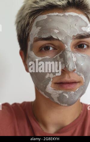 Cropped shot of woman apply grey green skincare clay mask on face ...