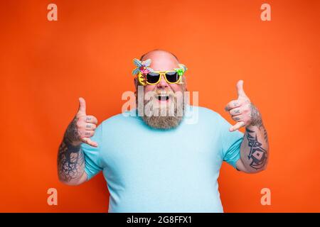 Fat happy man with beard, tattoos and sunglasses is ready for the ...