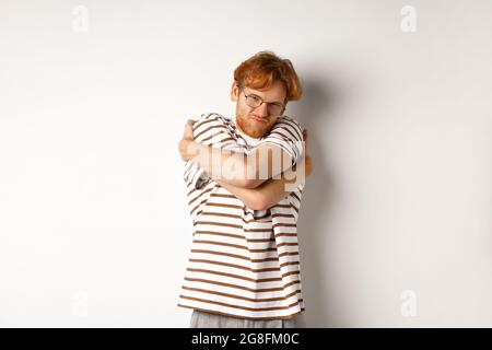 Reluctant young man with messy red hair unwilling do something, hugging ...