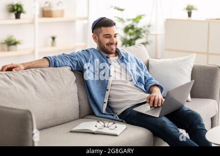 Smiling jewish man watching video on pc, drinking hot coffee Stock ...