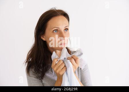 Caucasian woman sniffing clean white shirt on light background Stock ...