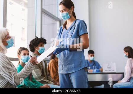Mature Patient Lady Signing Papers With Doctor In Hospital Waiting-Room ...