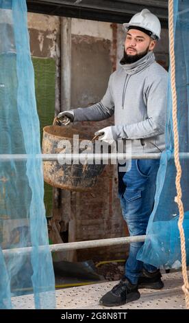 Contractor carrying bucket with cement mortar Stock Photo - Alamy