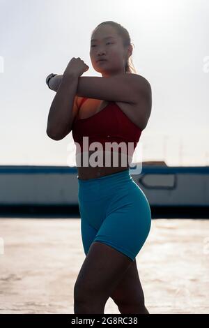 Asian woman stretching arms wearing headphones doing morning exercise ...