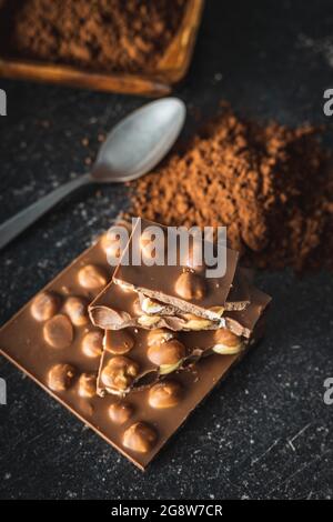 Nutty chocolate with hazelnuts and cocoa powder on black table Stock ...
