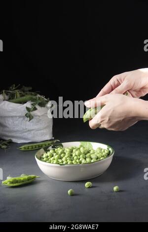 Woman hands open green pea pod. Green peas backgrounds Stock Photo - Alamy