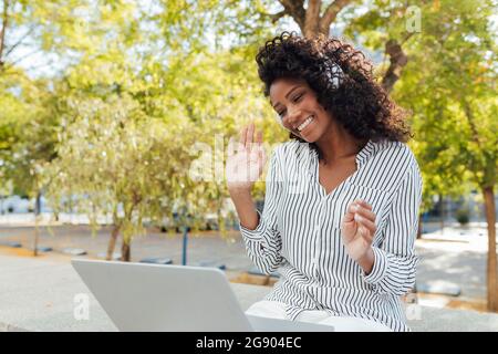 Curly haired businesswoman looking through window while contemplating ...