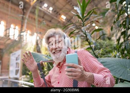 Happy man dancing and listening music in headphones, holding mobile ...