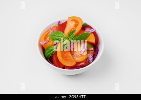 tasty tomato salad with red onion, mint leaves on white dish with fork ...
