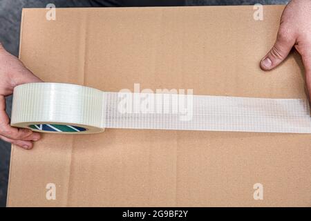 Packing Boxes with Tape. Sticking duct tape to a Kraft cardboard box ...