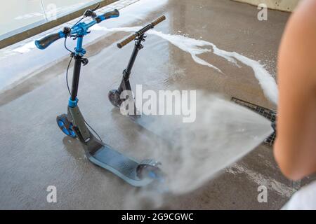 Washing a dirty scooter at a car wash under high pressure water. Care ...
