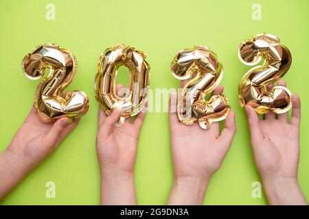 2022 figures on inflated golden balls with a bokeh of garland lights. The concept of a happy new ...