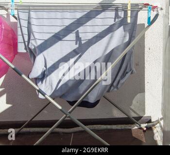 close up of washed linen hanging on red rope with clothepins outside ...