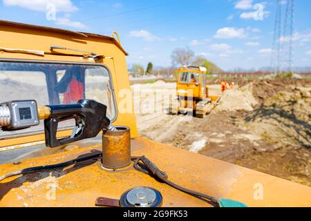 Fuel pump gun inserted in the reservoir of construction machine, pour ...
