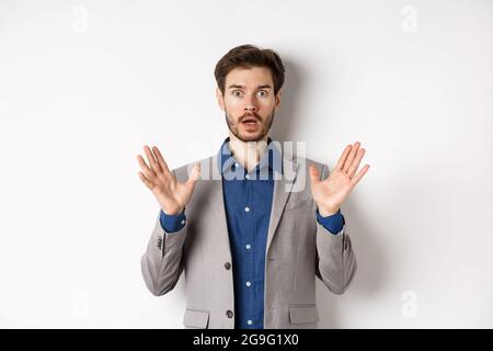 Surprised businessman in suit raising hands up and look excited ...