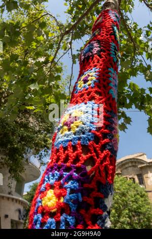 Colourful knitted and crocheted yarns wrap a trunk of a "Yarn Bombed ...