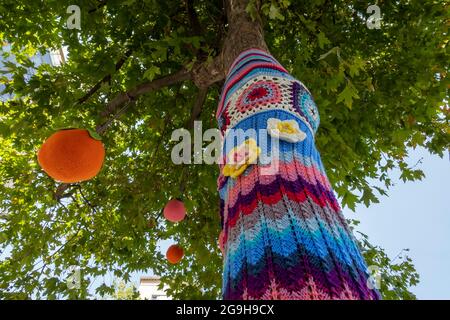 Colourful knitted and crocheted yarns wrap a trunk of a "Yarn Bombed ...