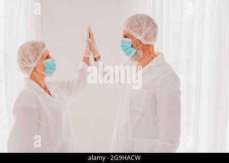 Doctors with mask and face protector give each other a 5 with their ...