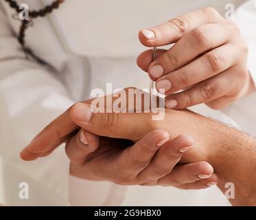 Doctor inserting needle into patient wrist for arterial line during ...