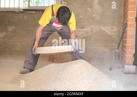 Young caucasian construction worker sieving sand during a house ...