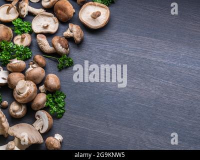 Different brown colored edible mushrooms on black table with herbs. Top ...