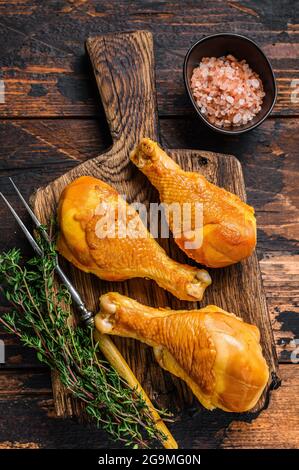 Marinated and Smoked chicken legs drumsticks on a wooden cutting board ...