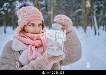 A happy woman stands with a lantern in her hands, a winter park with ...