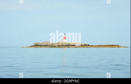 Old Muglins Lighthouse on the isolated island the backdrop of the blue ...
