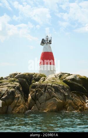 Old Muglins Lighthouse on the isolated island the backdrop of the blue ...