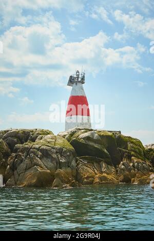 Old Muglins Lighthouse on the isolated island the backdrop of the blue ...