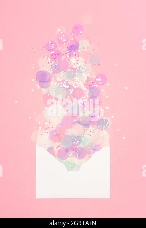 Sparkling confetti pouring out of envelope on pastel pink background ...