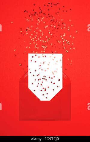 Red star shaped confetti pouring out of red envelope on pink background ...