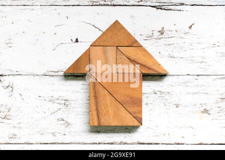 Tangram puzzle in direction arrow shape on old white wood background ...