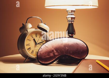 Stylish sleeping mask and alarm clock on table in bedroom Stock Photo ...