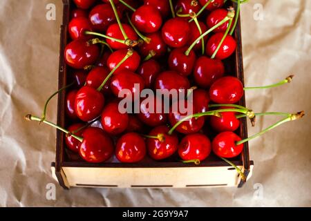 Cropped box, crape of dark red sweet cherries with tail on craft ...