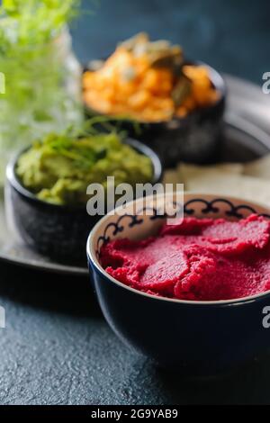 red beetroot hummus on blue background, lemon, sesame, olive oil, pita ...