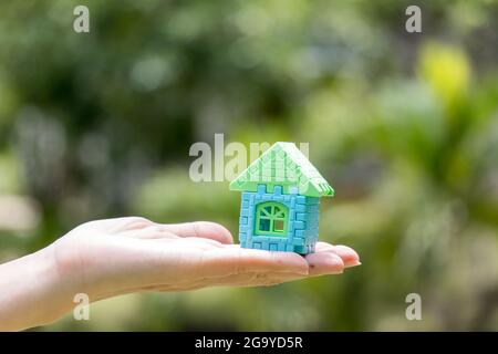 Woman hand hold home block model with blur green background (Concept ...