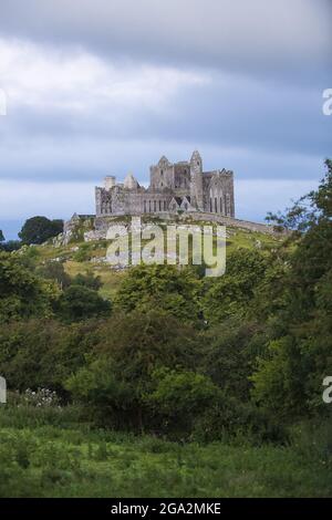 The ancient Rock of Cashel on the hilltop with two birds flying against ...
