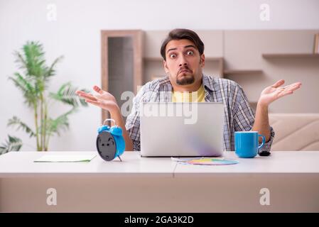 Young freelancer in time management concept at home Stock Photo - Alamy