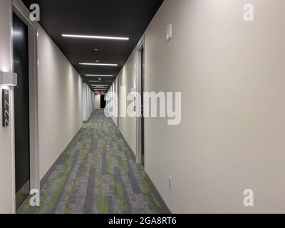 A sterile hallway with white walls and grey striped carpet in an ...