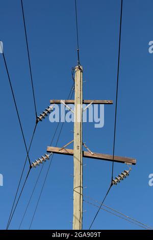 Photograph of a wooden telephone post and cables against a blue sky ...