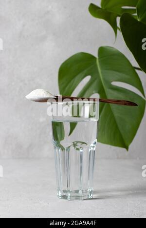 Glass with collagen dissolved in water and collagen protein powder on ...
